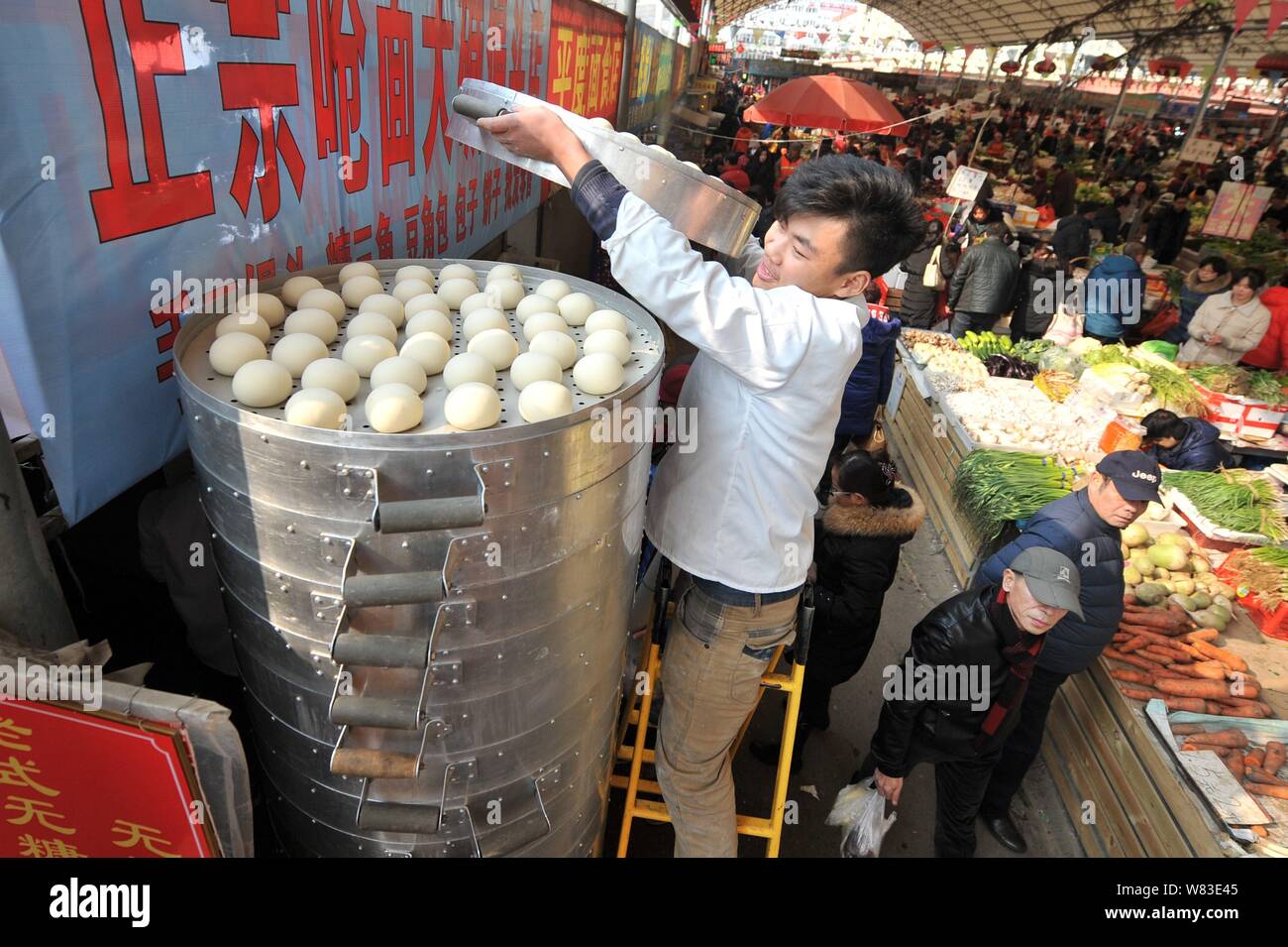 --FILE--A Chinese worker stacks up steamer trays to steam buns at a ...
