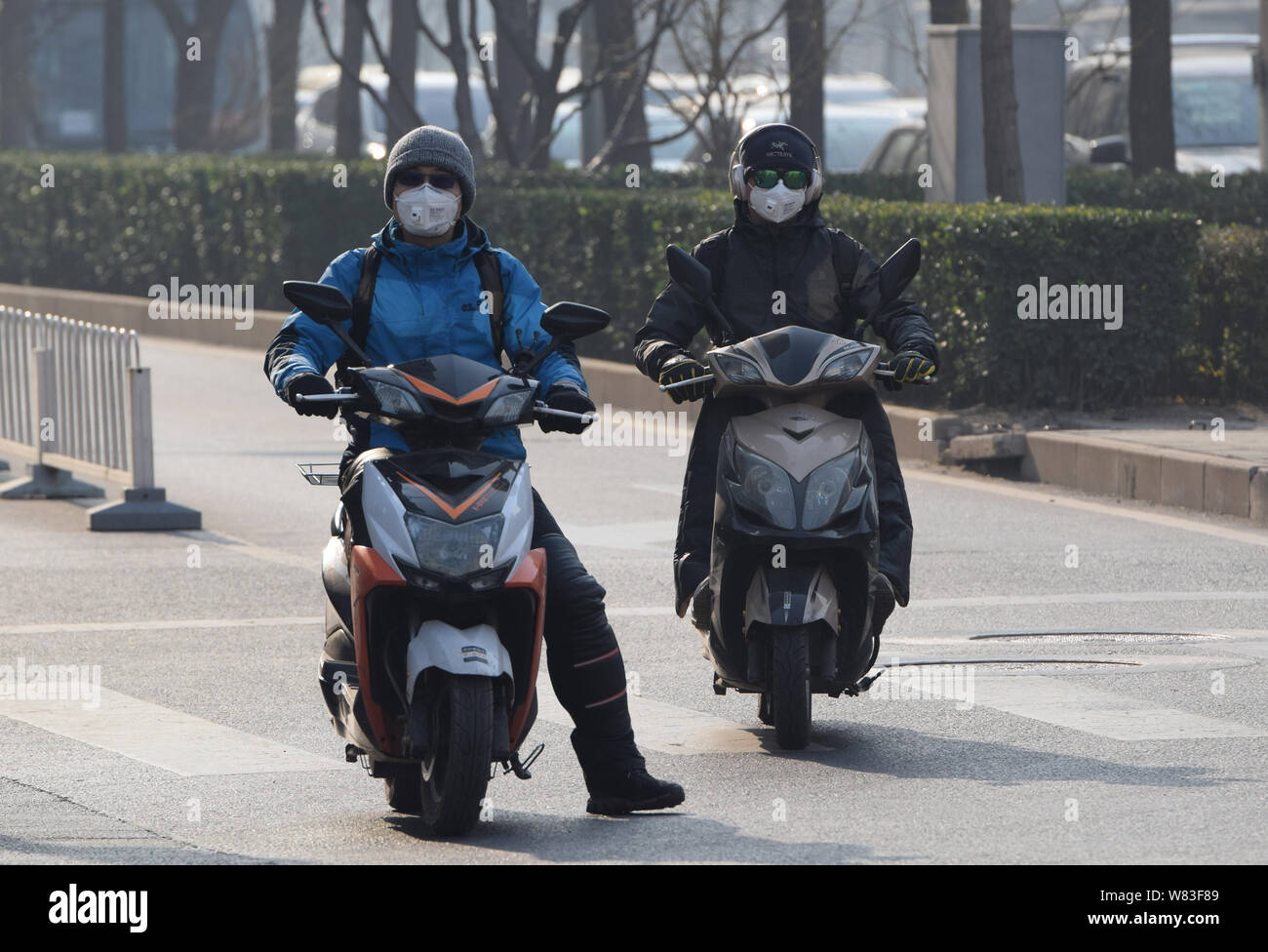 Cyclists wearing face masks against air pollution ride electric bike on ...