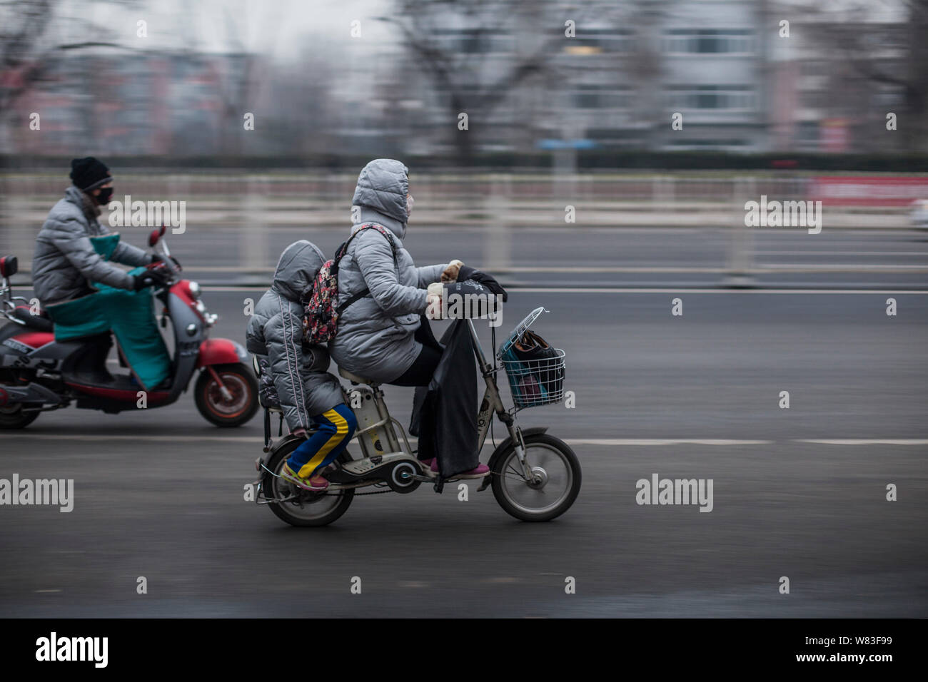 Cyclists wearing face masks against air pollution ride electric bikes ...