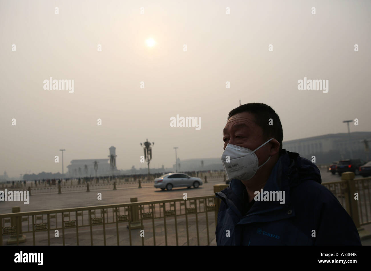 A pedestrian wearing a face mask against air pollution walks past the ...