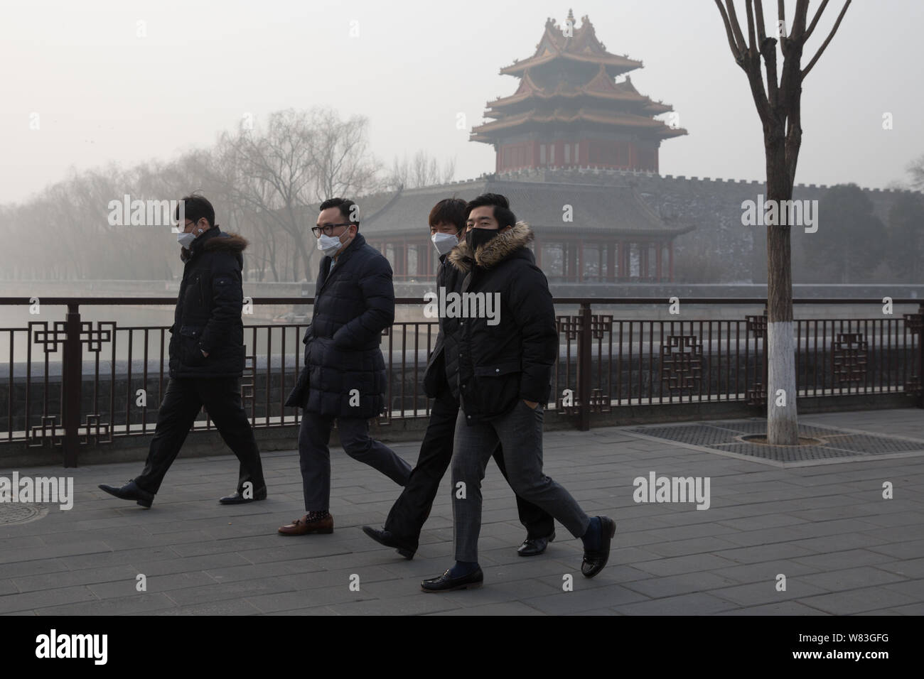 Pedestrians wearing face masks against air pollution walk past the ...
