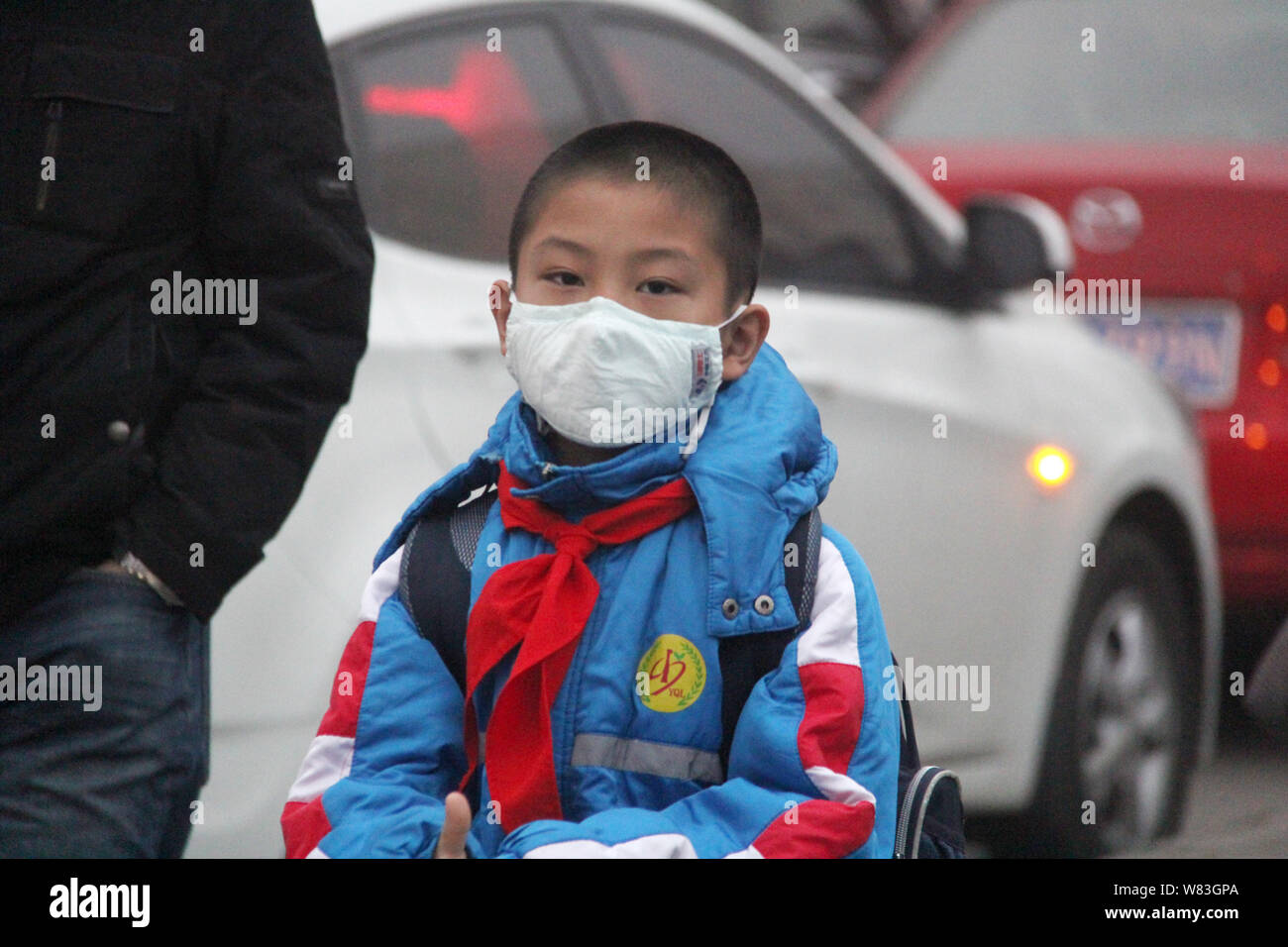 A young Chinese boy wearing a face mask against air pollution walks on ...