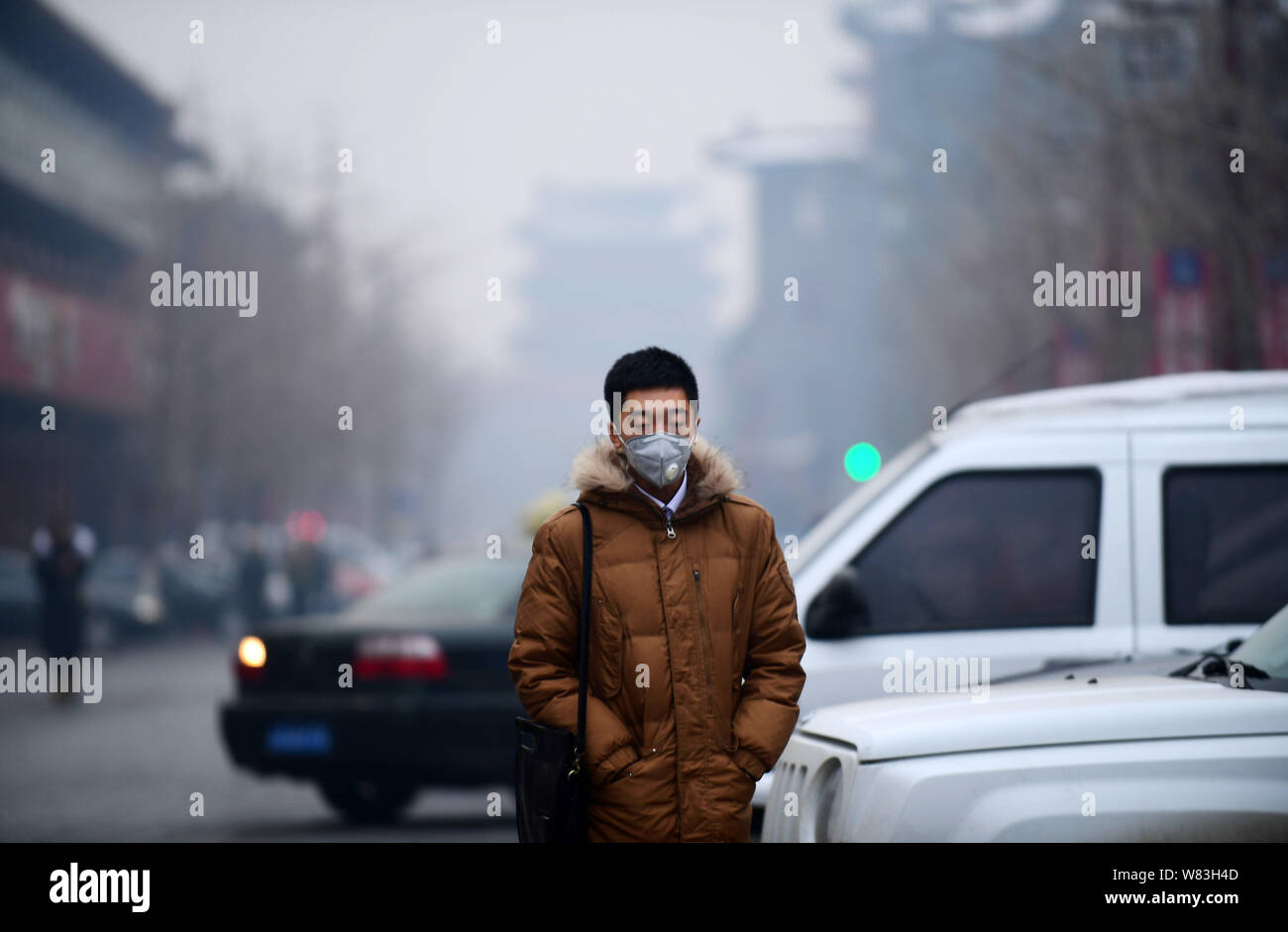 A pedestrian wearing a face mask against air pollution walks on the ...
