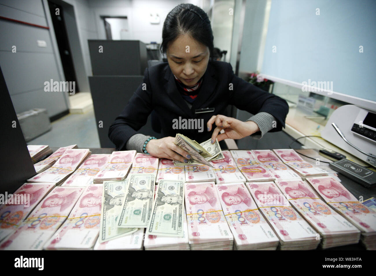 --FILE--A Chinese clerk counts US dollar banknotes over RMB (renminbi ...