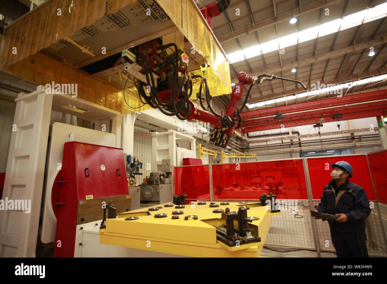 --FILE--A Chinese worker checks a welding robot arm at a factory in ...