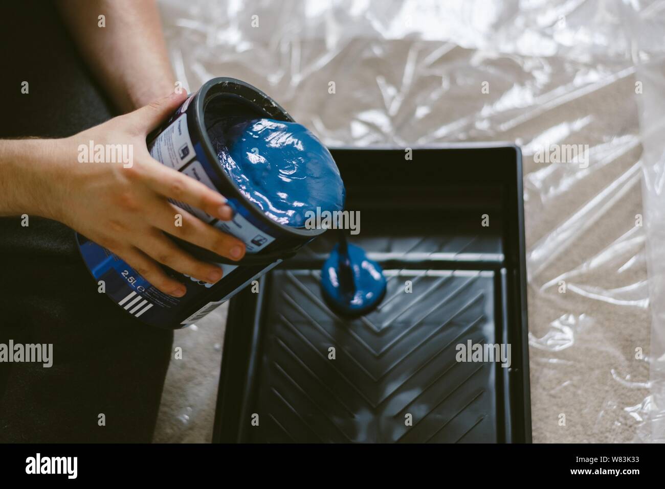Person holding a bucket of blue wall paint Stock Photo - Alamy