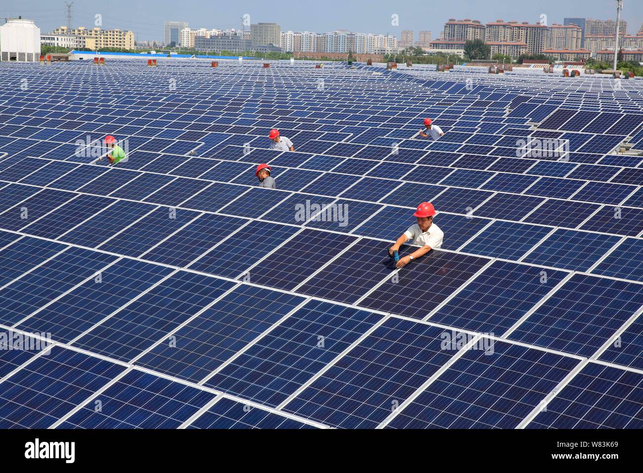 --FILE--Chinese workers install solar panels on the rooftop of a ...