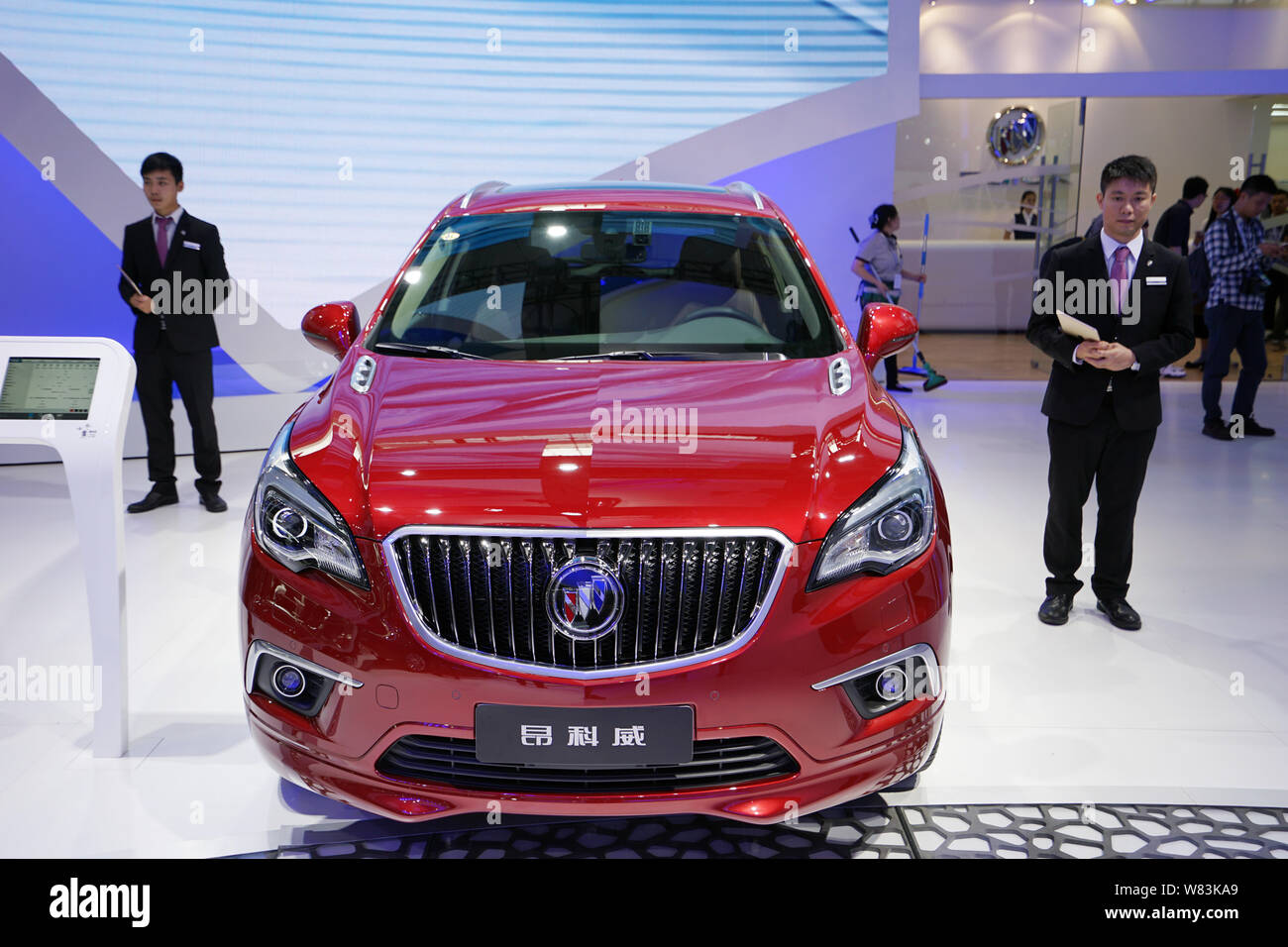 --FILE--Chinese employees pose next to a Buick Envision of SAIC-GM, a ...