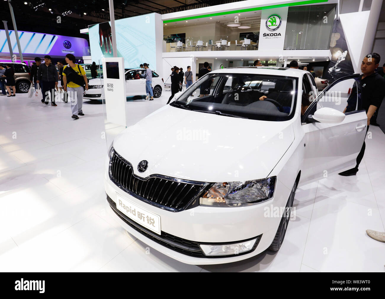--FILE--Visitors try out or look at Skoda cars of SAIC Volkswagen, a ...