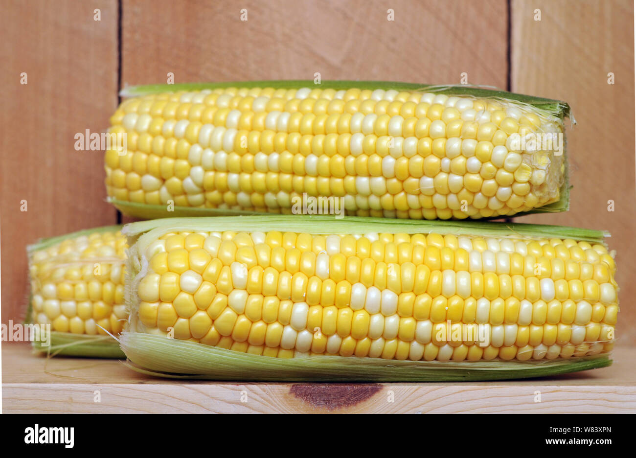 Three fresh corns on wooden shelf Stock Photo - Alamy