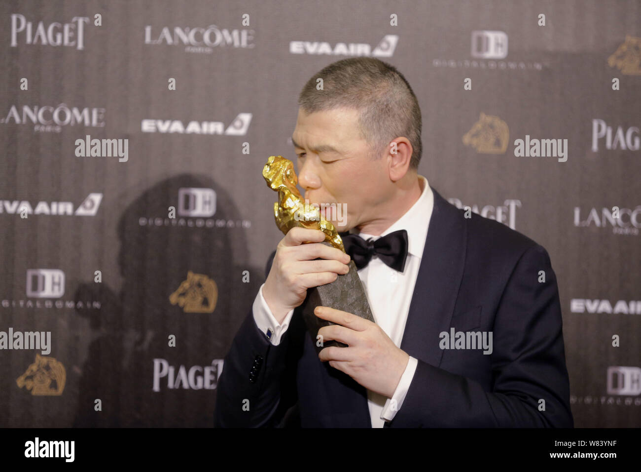 Chinese director Feng Xiaogang kisses his trophy of the Best Director ...