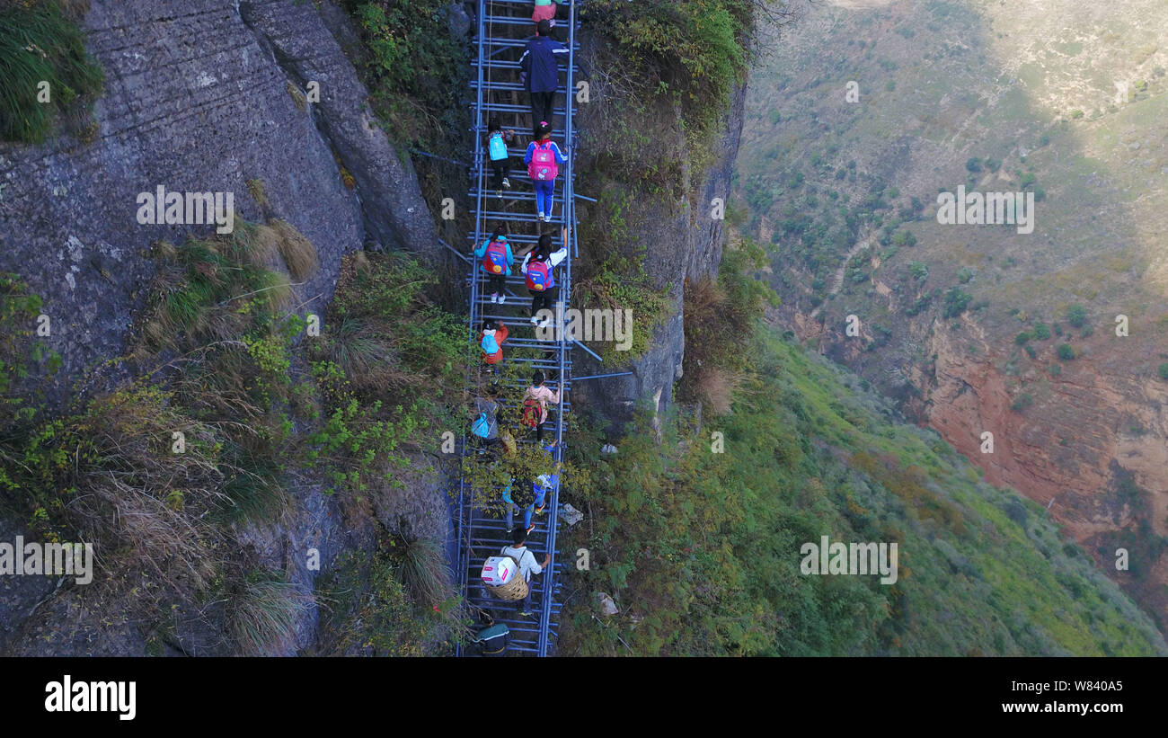 Local children climb up an 800-meter cliff on a steel ladder in a ...
