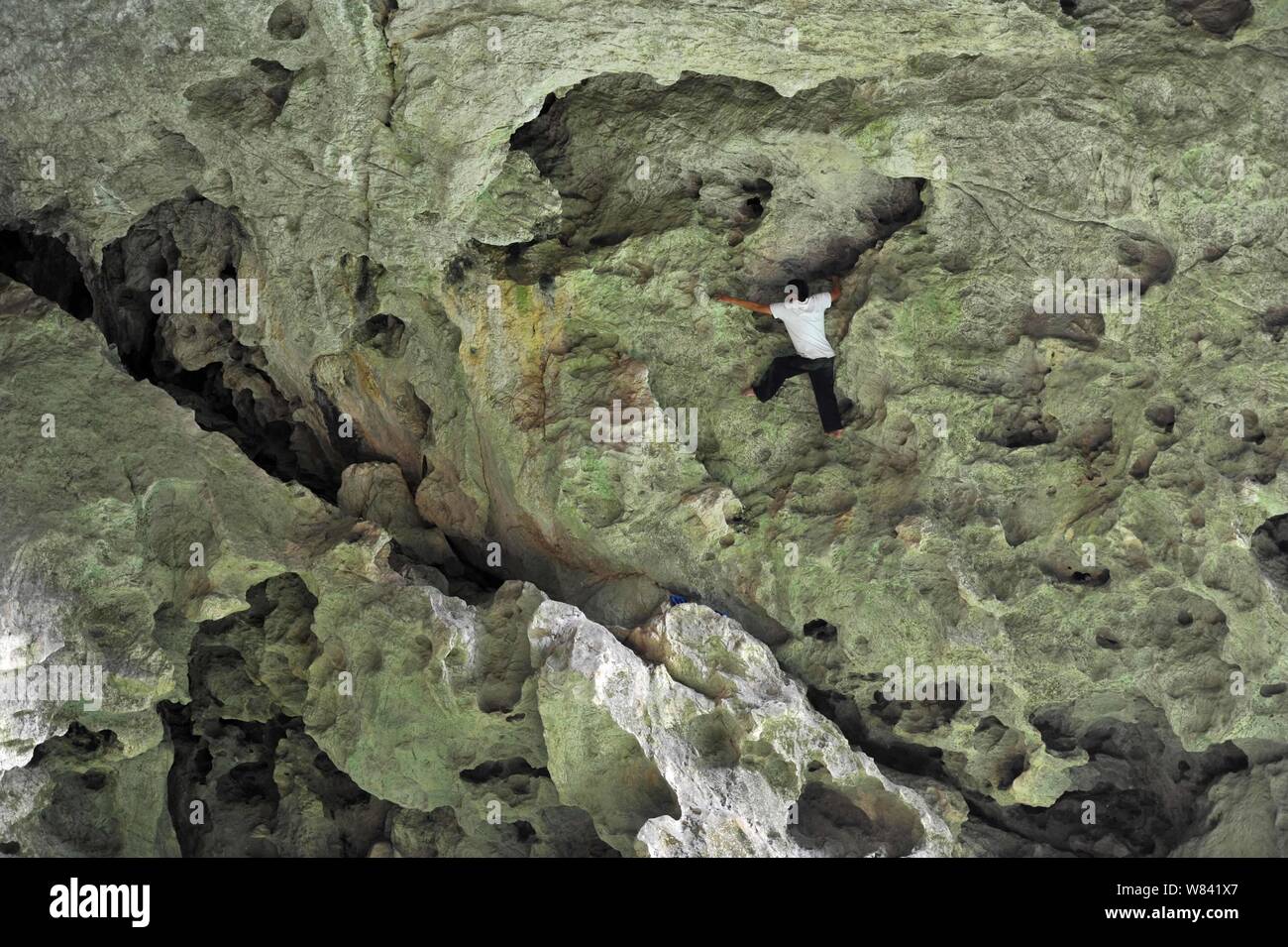 Chinese man Huang Xiaobao of Miao ethnic minority climbs the cliff in a ...