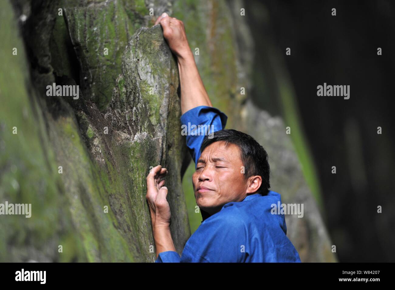 Chinese man Huang Xiaobao of Miao ethnic minority climbs the cliff in a ...