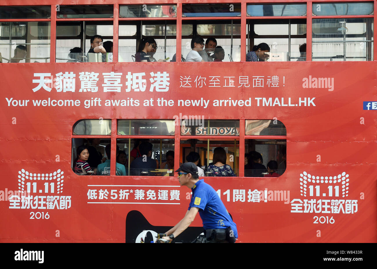 --FILE--A man cycles past a double-decker tram with advertisements for the 2016 Tmall 11.11 ...
