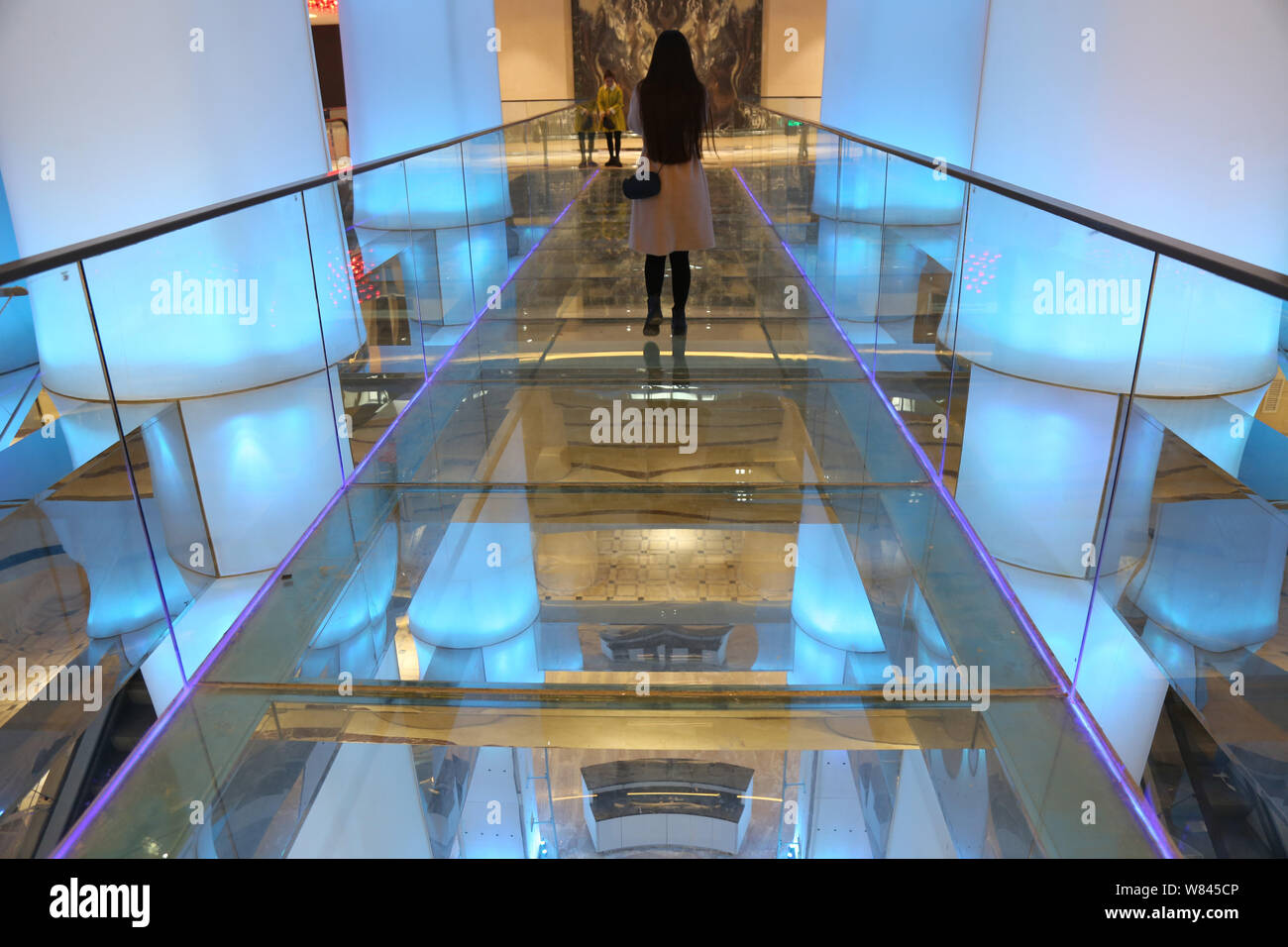 A Chinese student walks through a glass bridge in the new library at ...