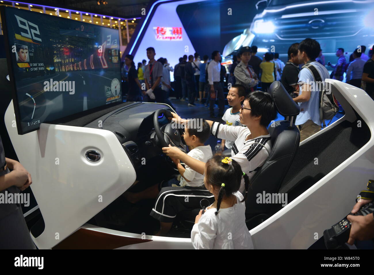 Visitors try out virtual reality (VR) devices in a model car to feel ...