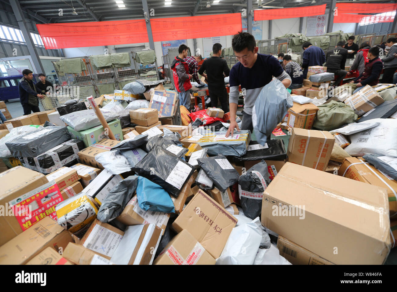 Chinese workers sort piles of parcels, most of which are from Singles Day online shopping, at a ...