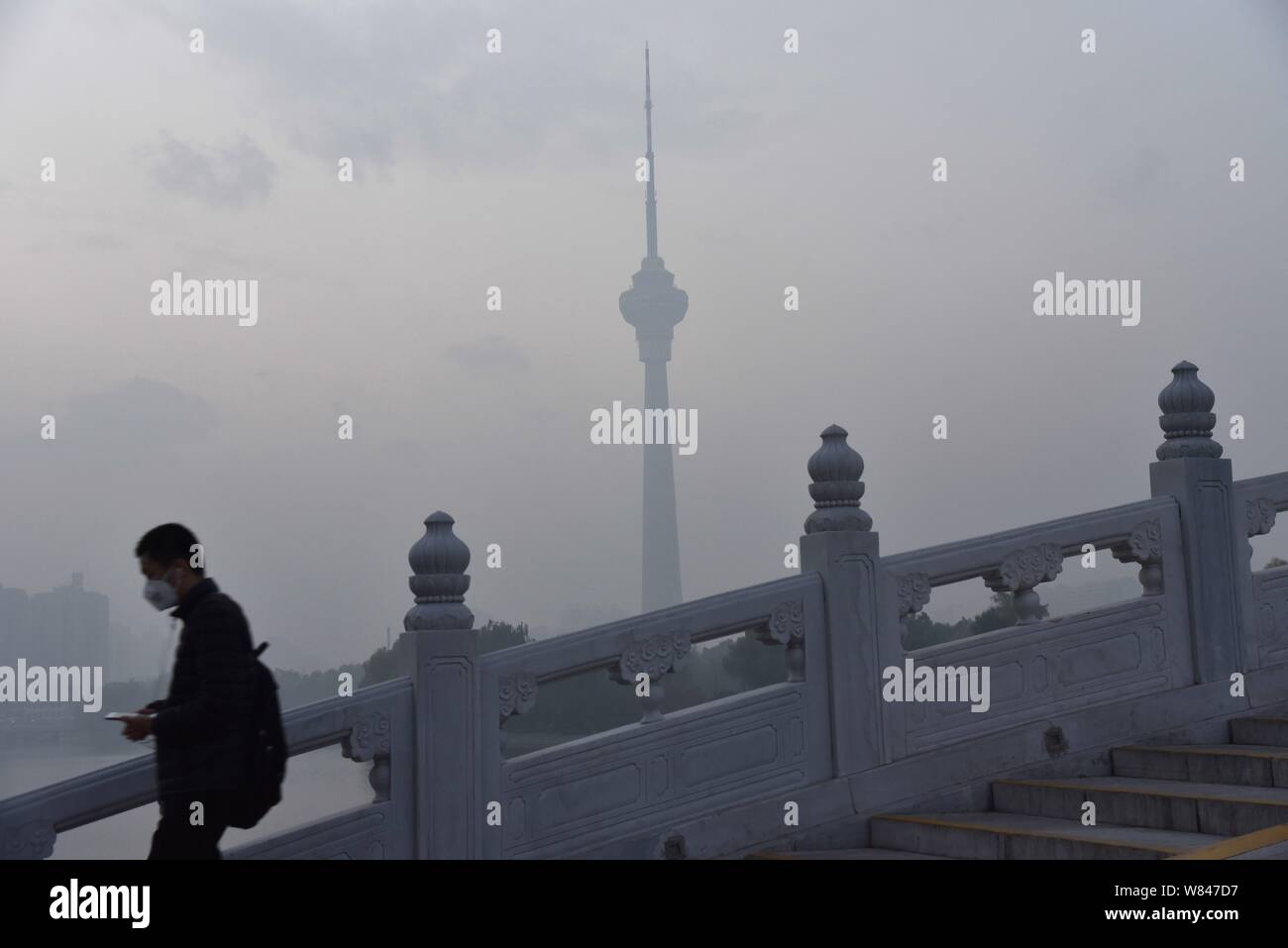 --FILE--A pedestrian wearing a face mask walks on a road in heavy smog ...