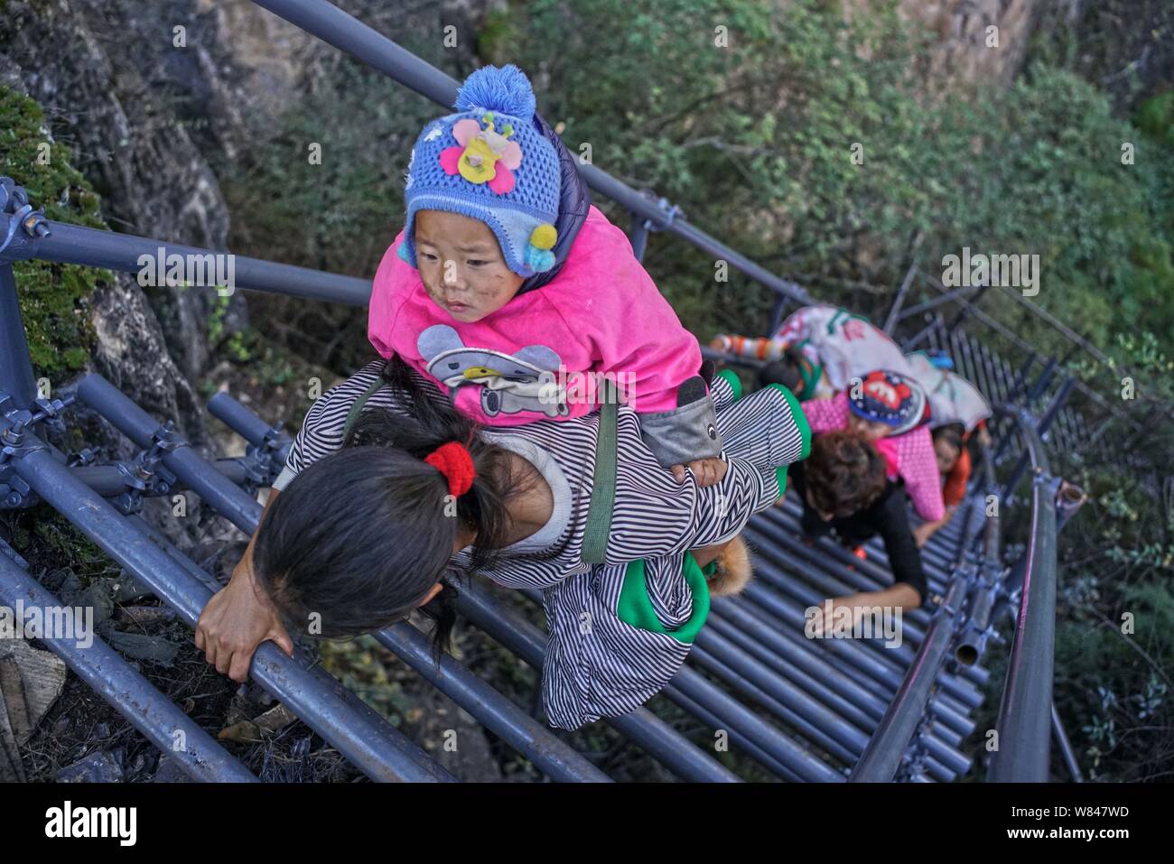 Local villagers carrying their children climb up an 800-meter cliff on ...