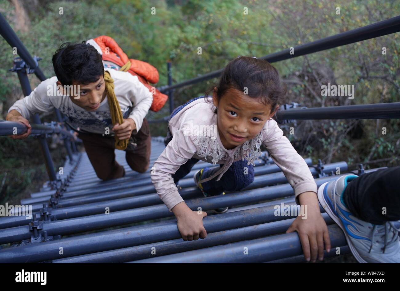 A local boy climbs up an 800-meter cliff on a steel ladder with his ...