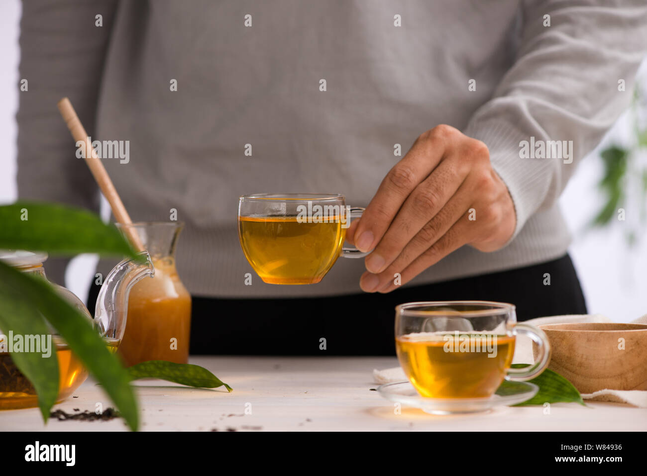 Male hands holding cup of tea glass on light background Stock Photo - Alamy