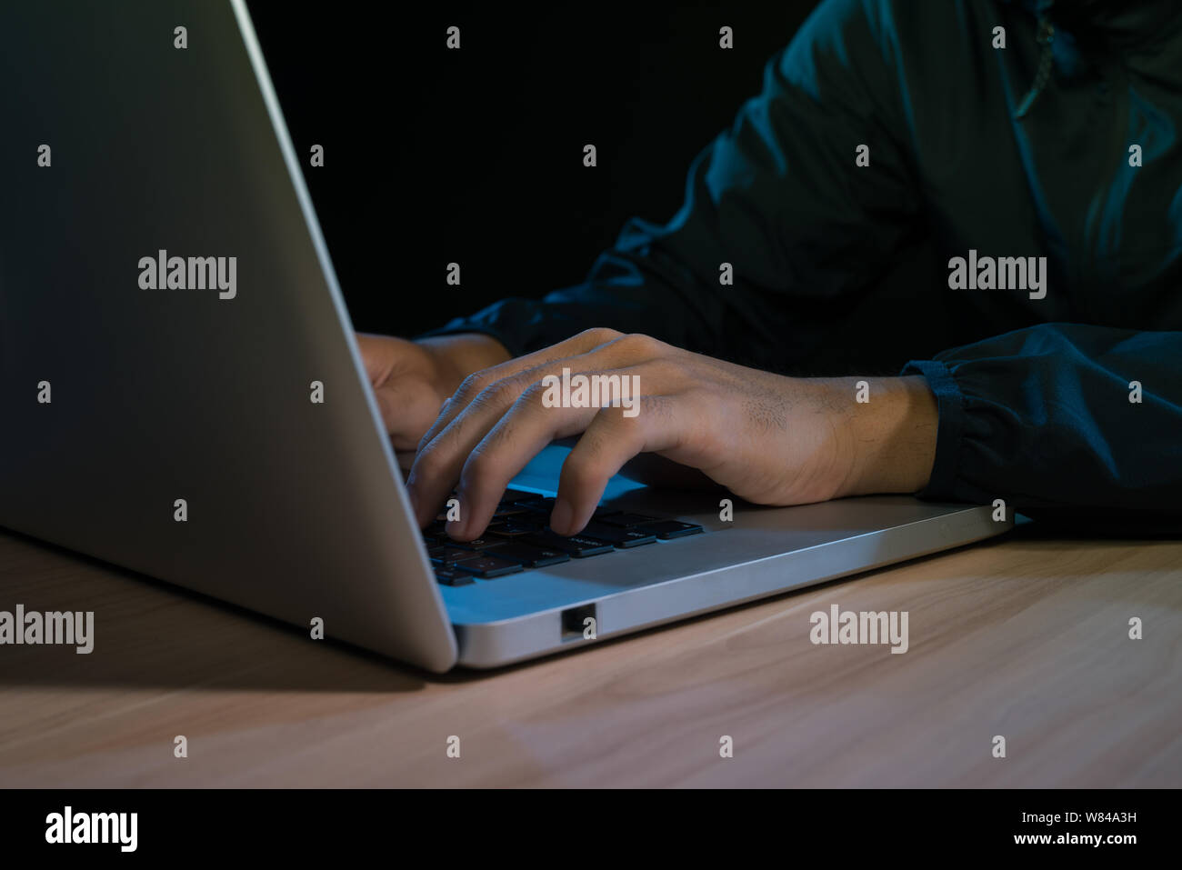 Man working on laptop in dark room Stock Photo - Alamy