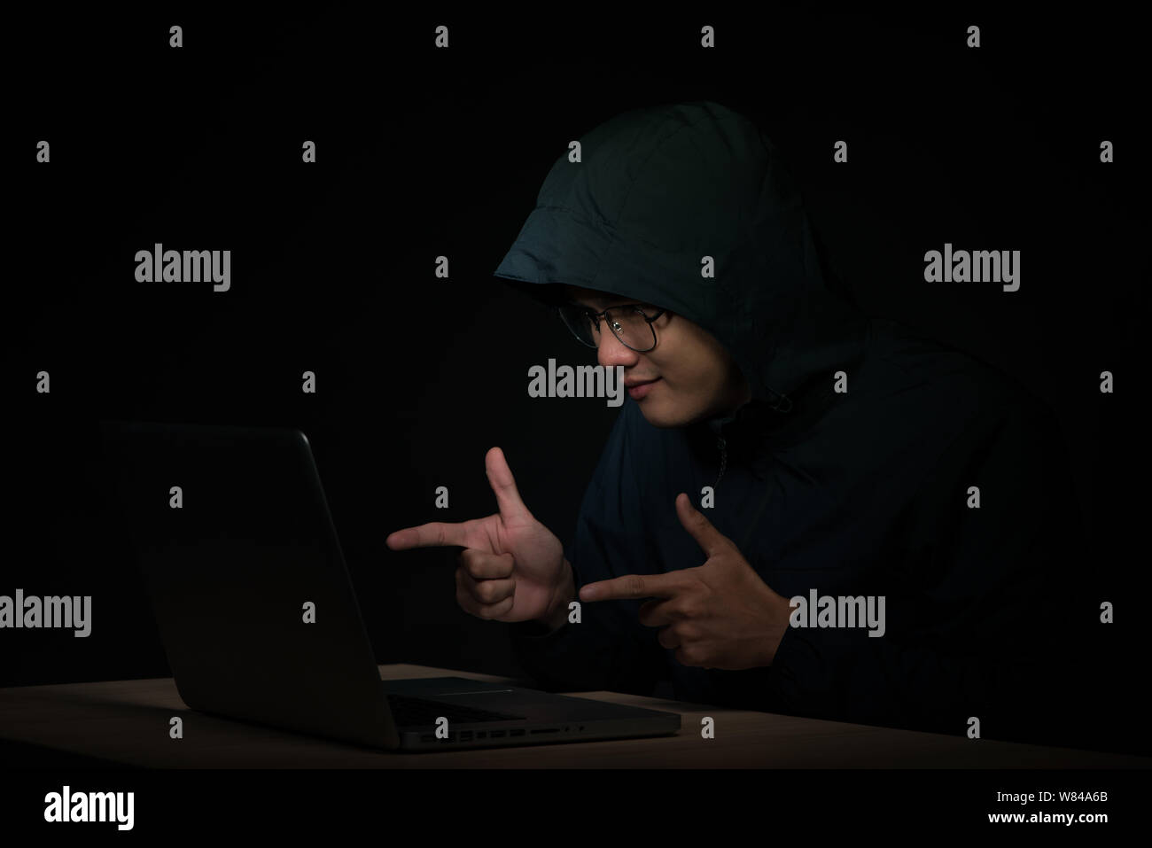 Successful male hacker poses in front of laptop computer, clenches ...
