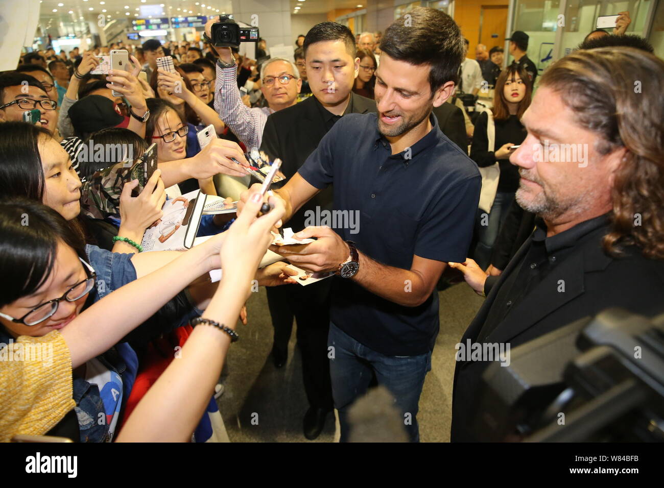 Novak Djokovic of Serbia, center, signs autographs for fans after ...