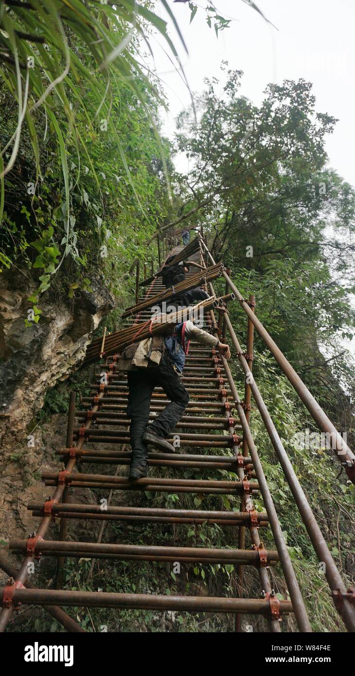 Chinese villagers carrying steel pipes climb up a steel ladder on the ...