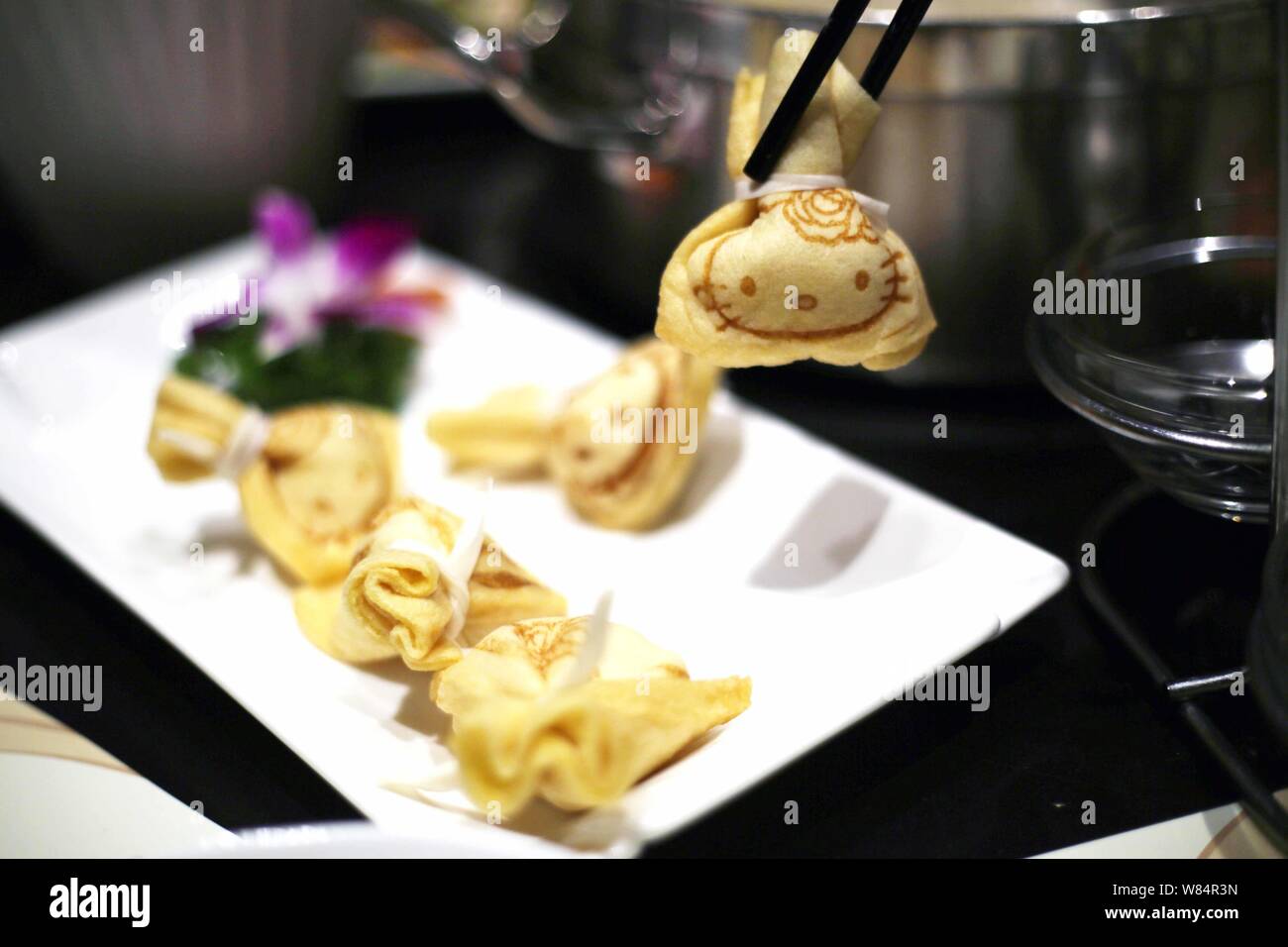 A customer shows a plate of food at the Hello Kitty hot-pot restaurant ...