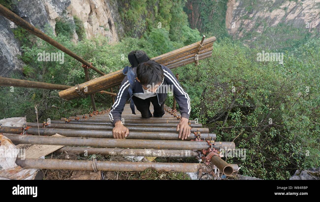 A Chinese villager carrying steel pipes climbs up a steel ladder on the ...
