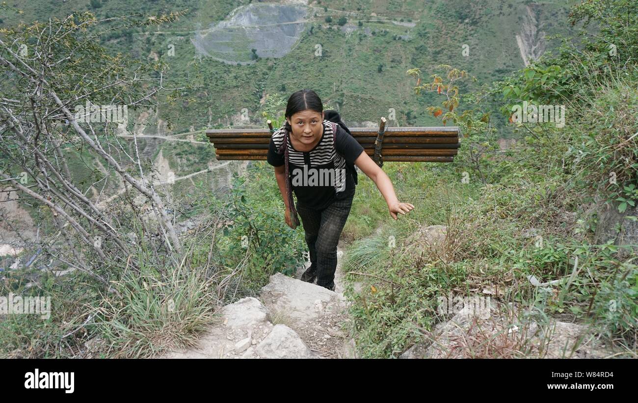 A Chinese villager carrying steel pipes climbs up a mountain to deliver ...