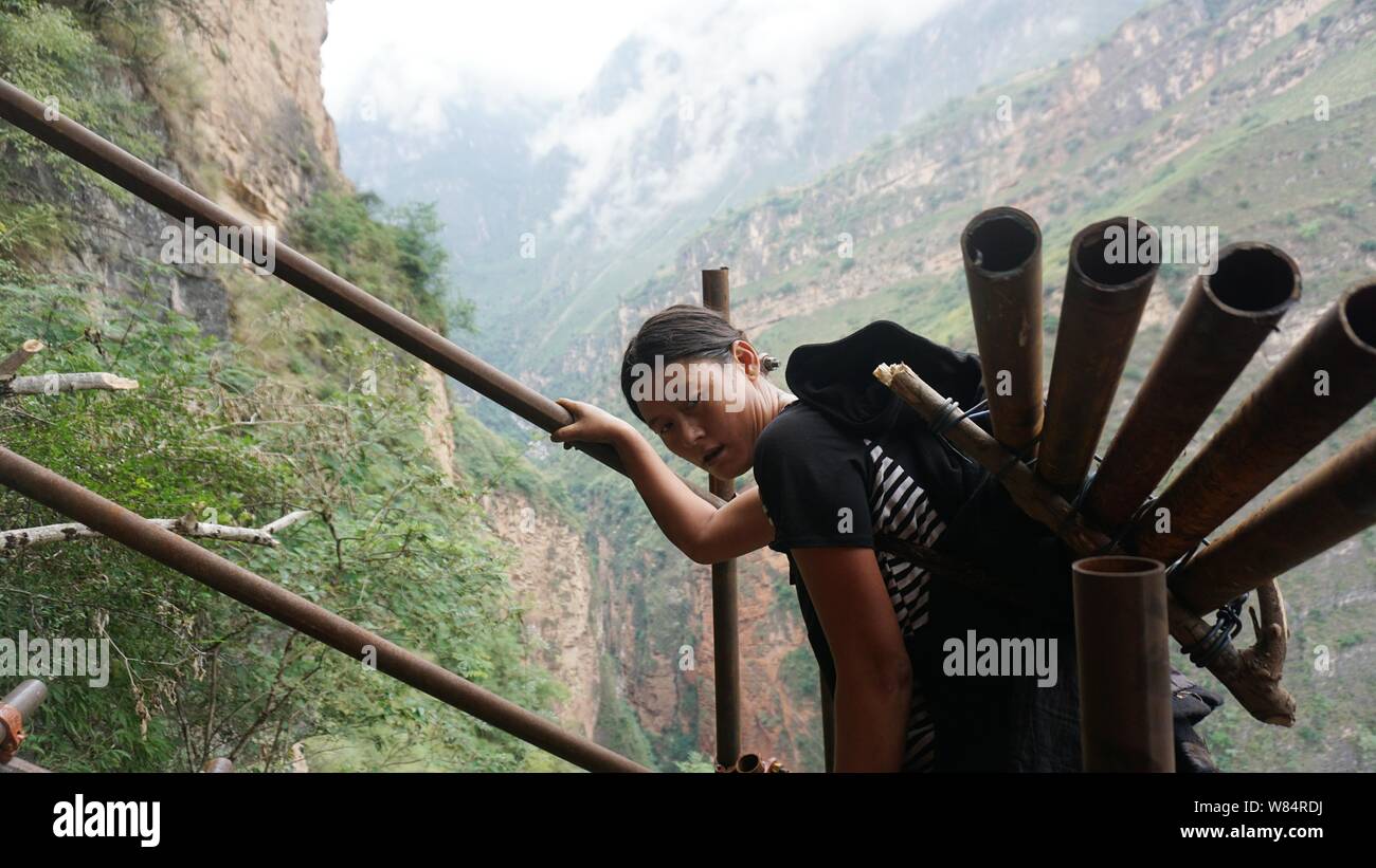 A Chinese villager carrying steel pipes climbs up a steel ladder on the ...
