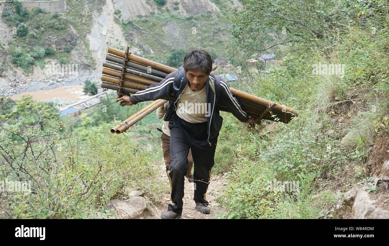 Chinese villagers carrying steel pipes walk on a path to deliver the ...