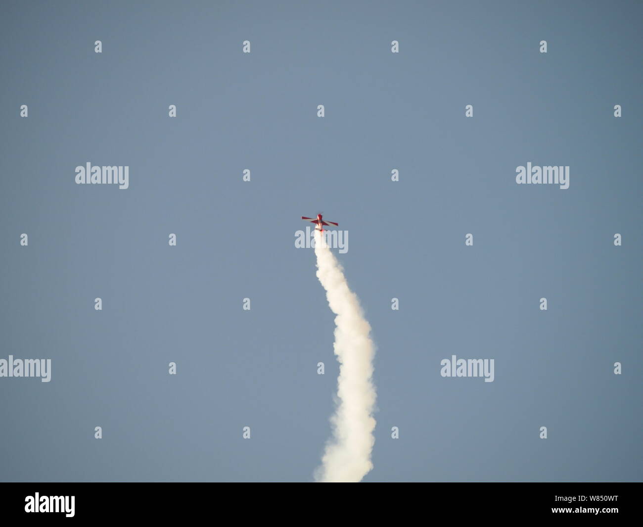 Single red and white plane in aerobatic display with smoke trail Stock ...