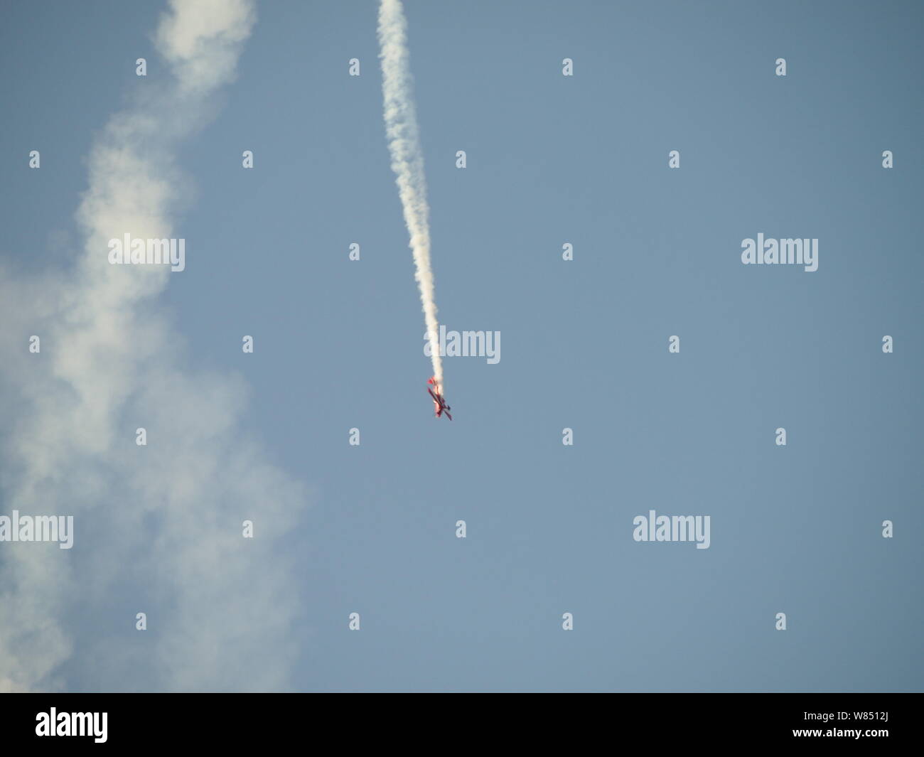 Single red and white plane in aerobatic display with smoke trail Stock ...