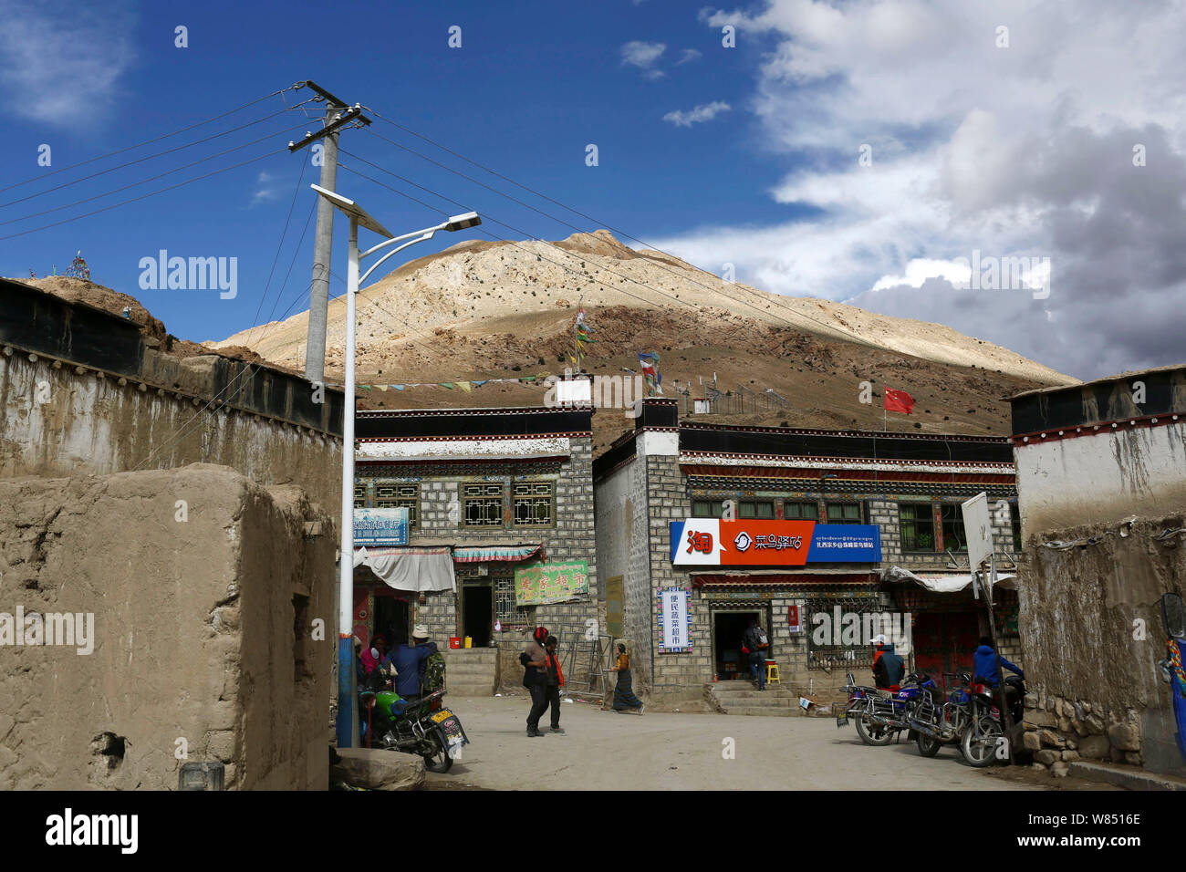 Local Tibetan residents walk past the Qomolangma delivery service ...