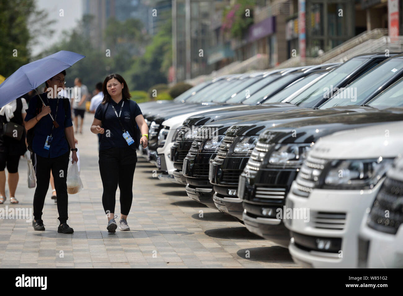 Chinese visitors look at Land Rover and Range Rover SUVs on display ...