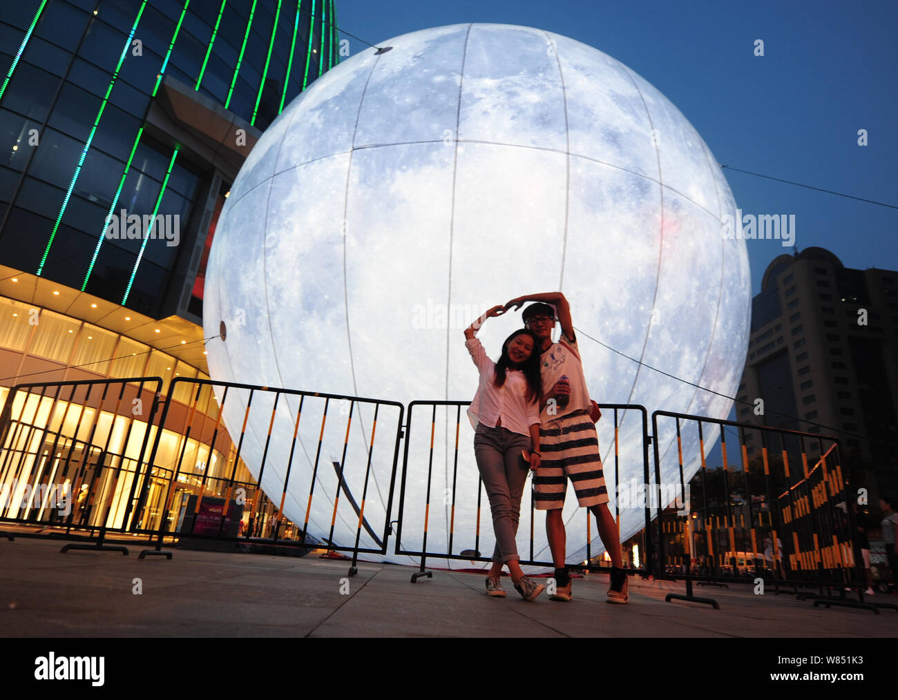 A couple poses for selfies in front of a giant sphere simulating the ...