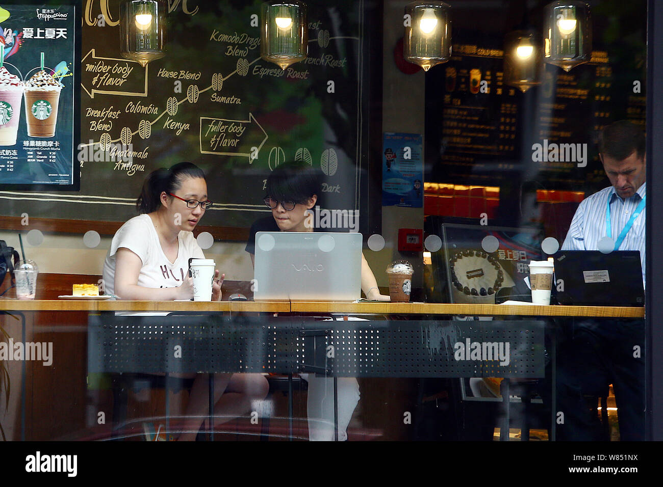 --FILE--Customers enjoy coffee and use their laptop computers at a cafe ...