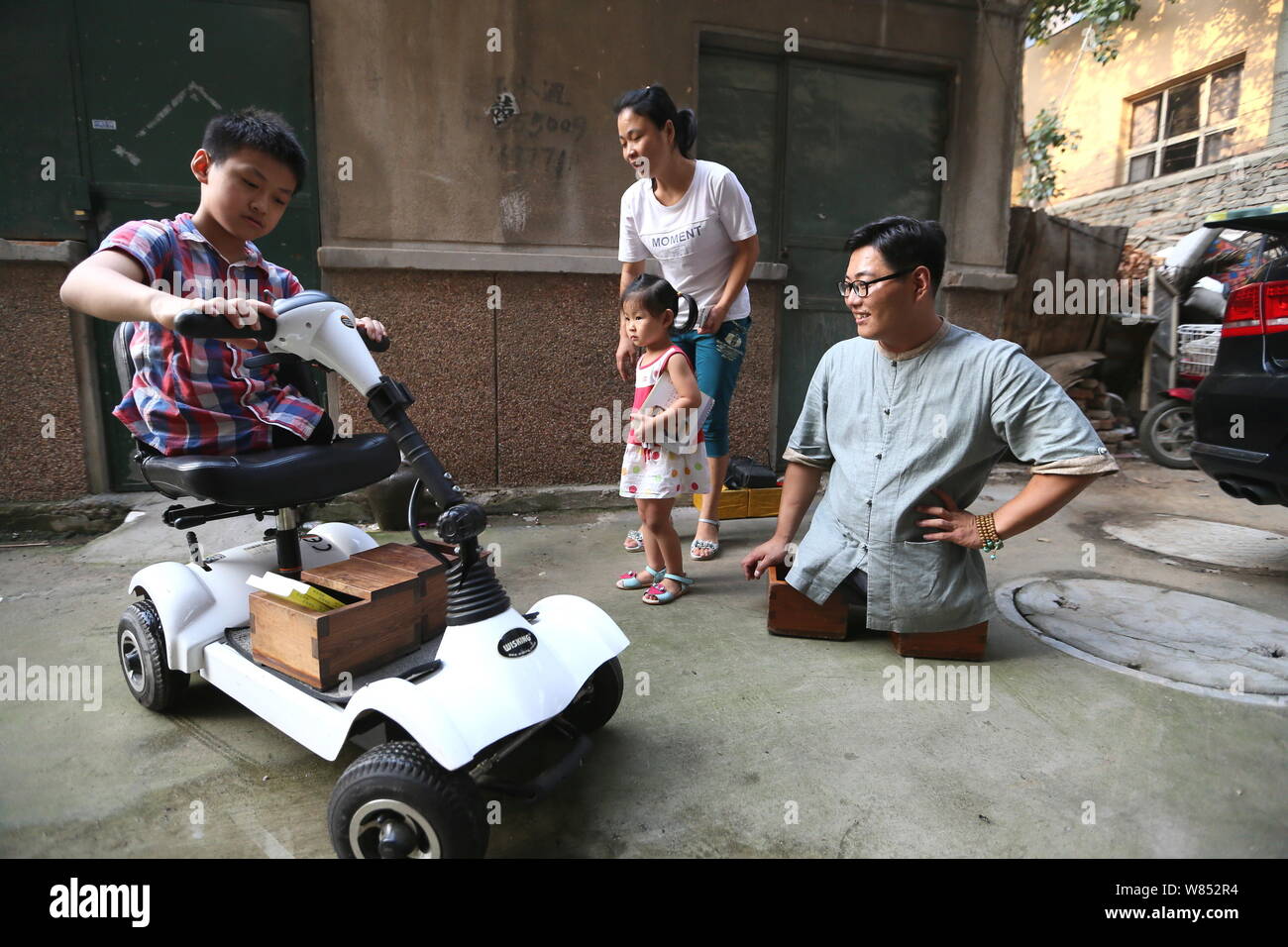 Legless Chinese boy Gao Zhiyu, left, tries out an electric vehicle ...