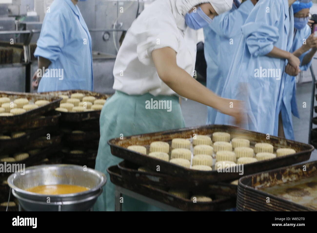 A Chinese worker smears egg yolk on mooncakes for the upcoming Mid ...