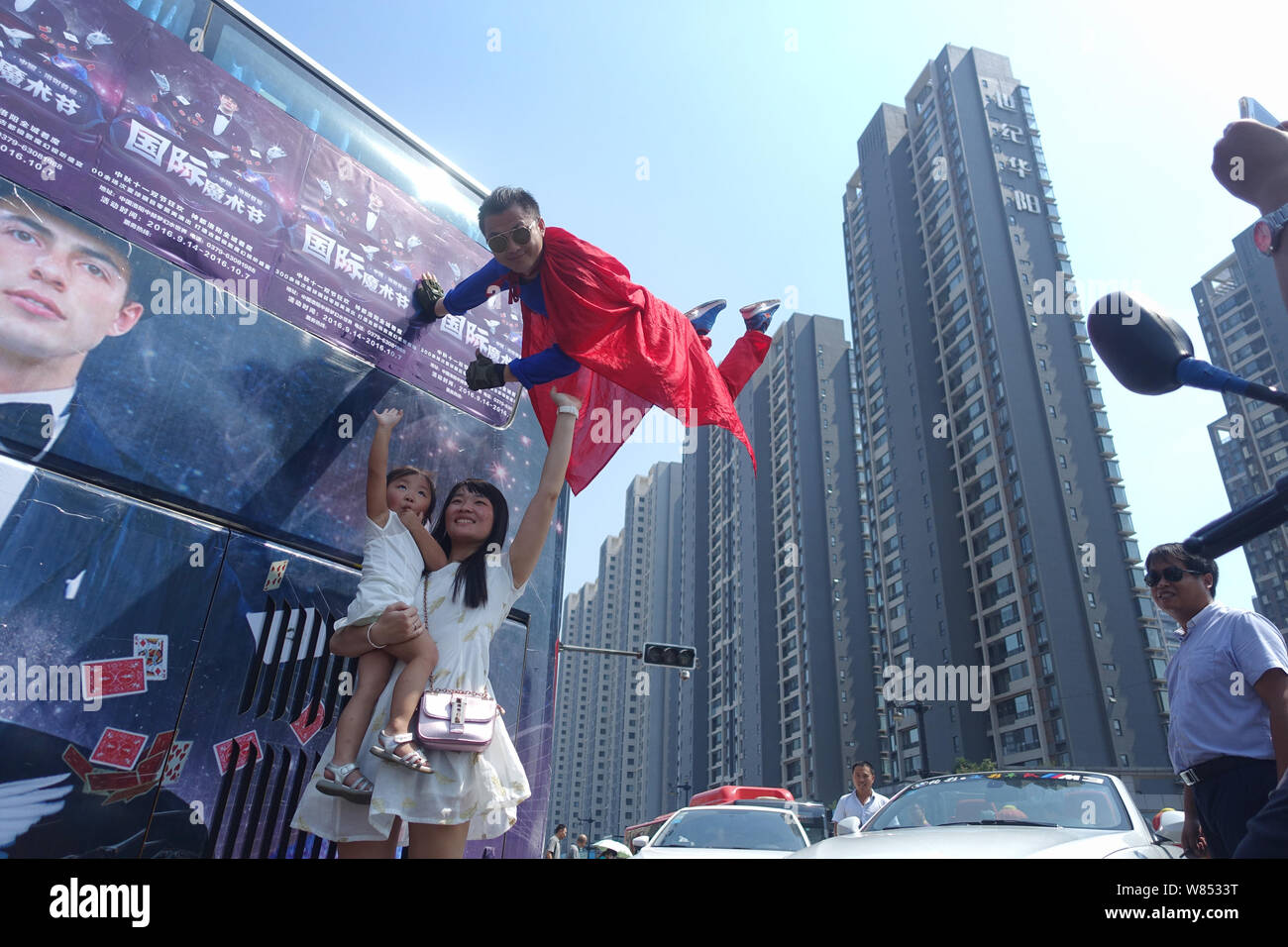 Pedestrians look at Chinese magician Zhou Jieming dressed like Superman ...