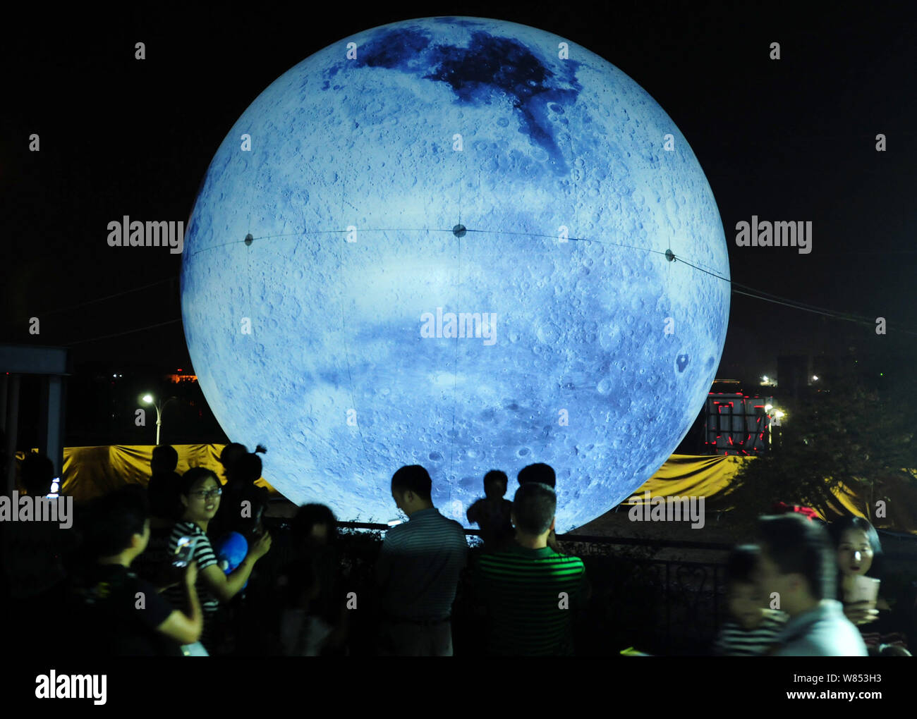 Local Chinese residents look at an illuminated man-made moon on the ...