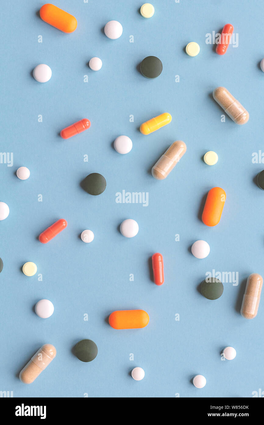 Different size and color pills on blue background Stock Photo - Alamy