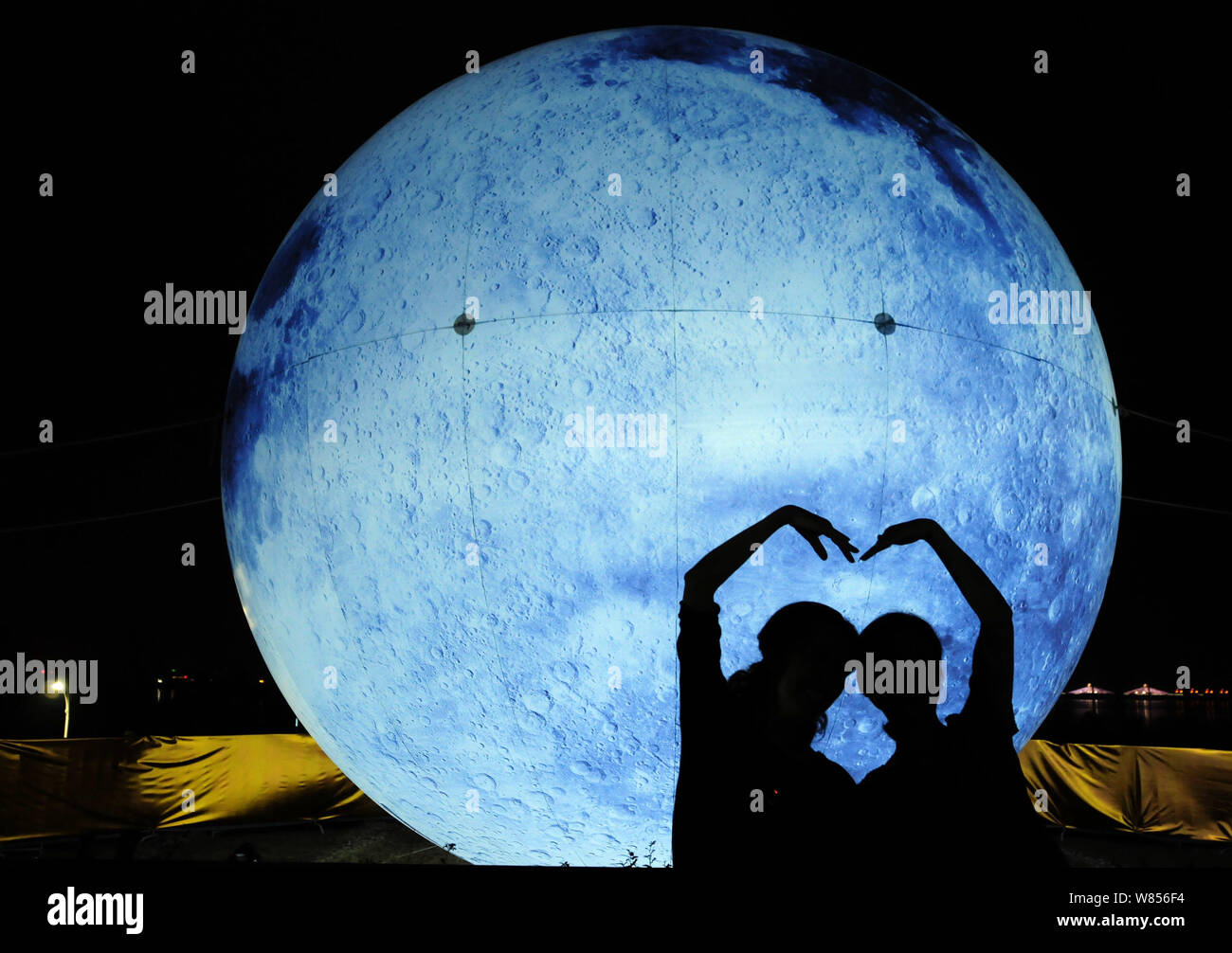 Local Chinese residents pose for photos in front of an illuminated man ...