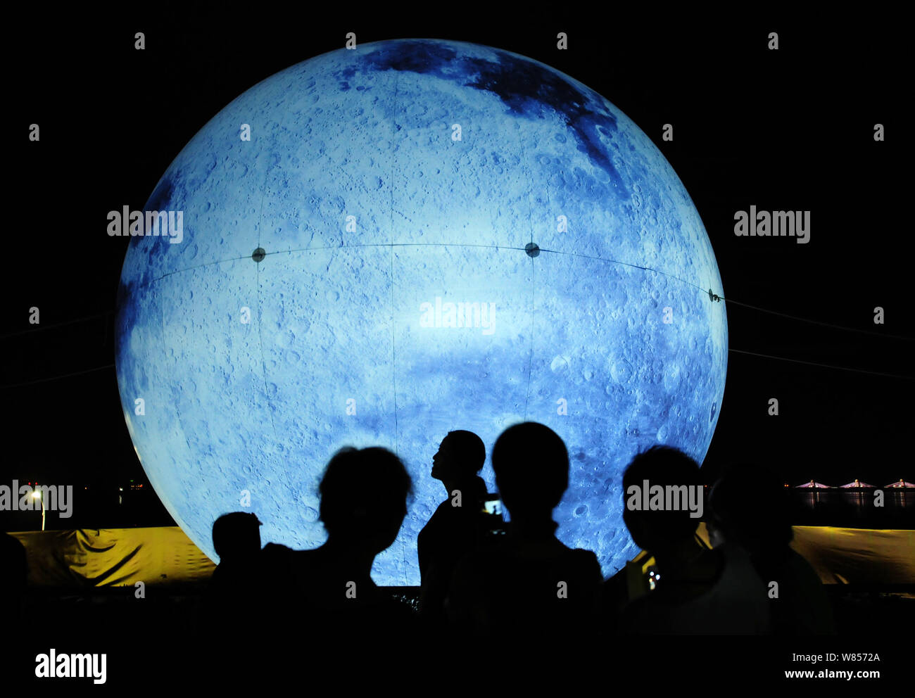Local Chinese residents look at an illuminated man-made moon on the ...