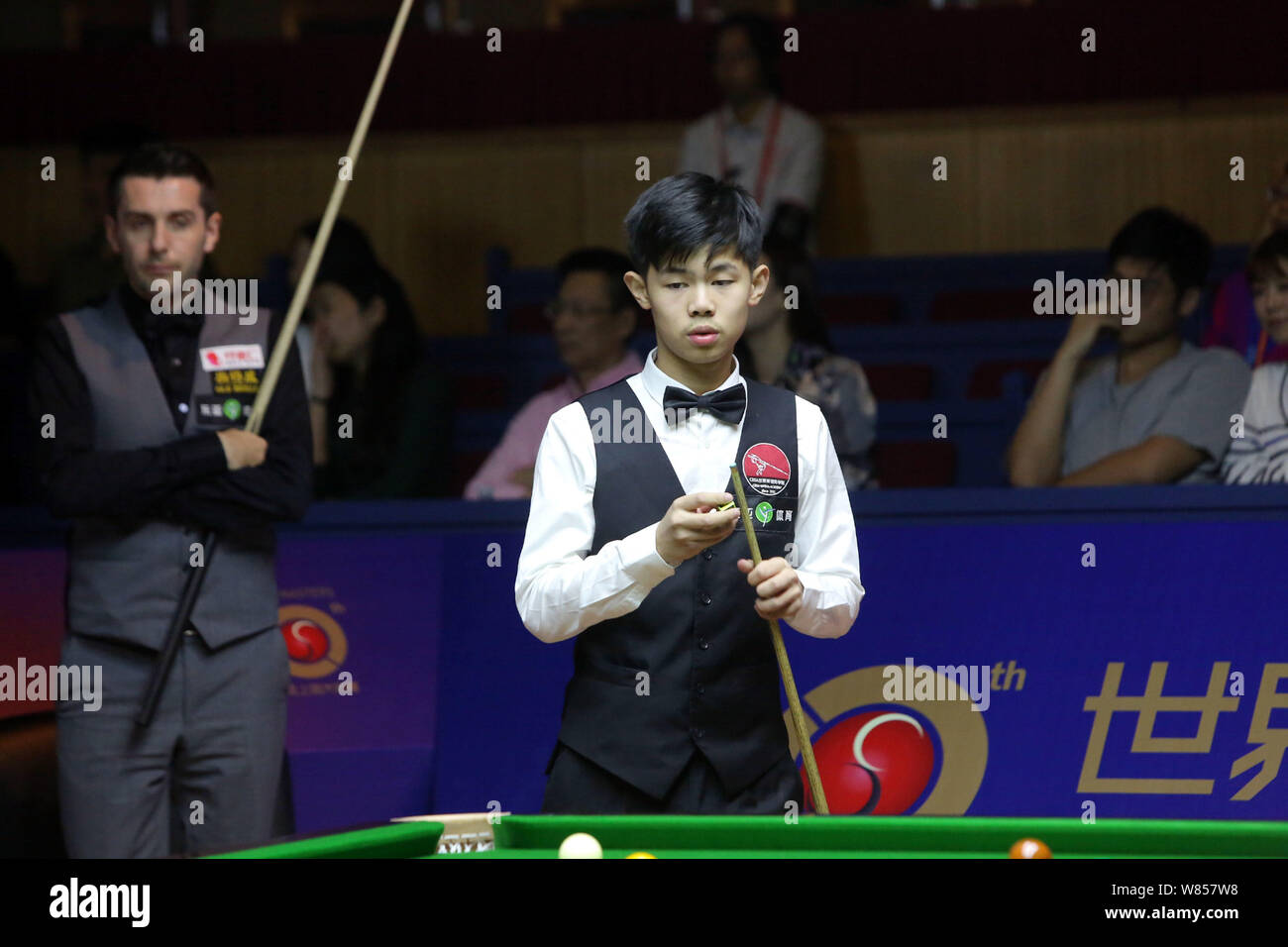 Yuan Sijun of China chalks his cue as he considers a shot against Mark ...