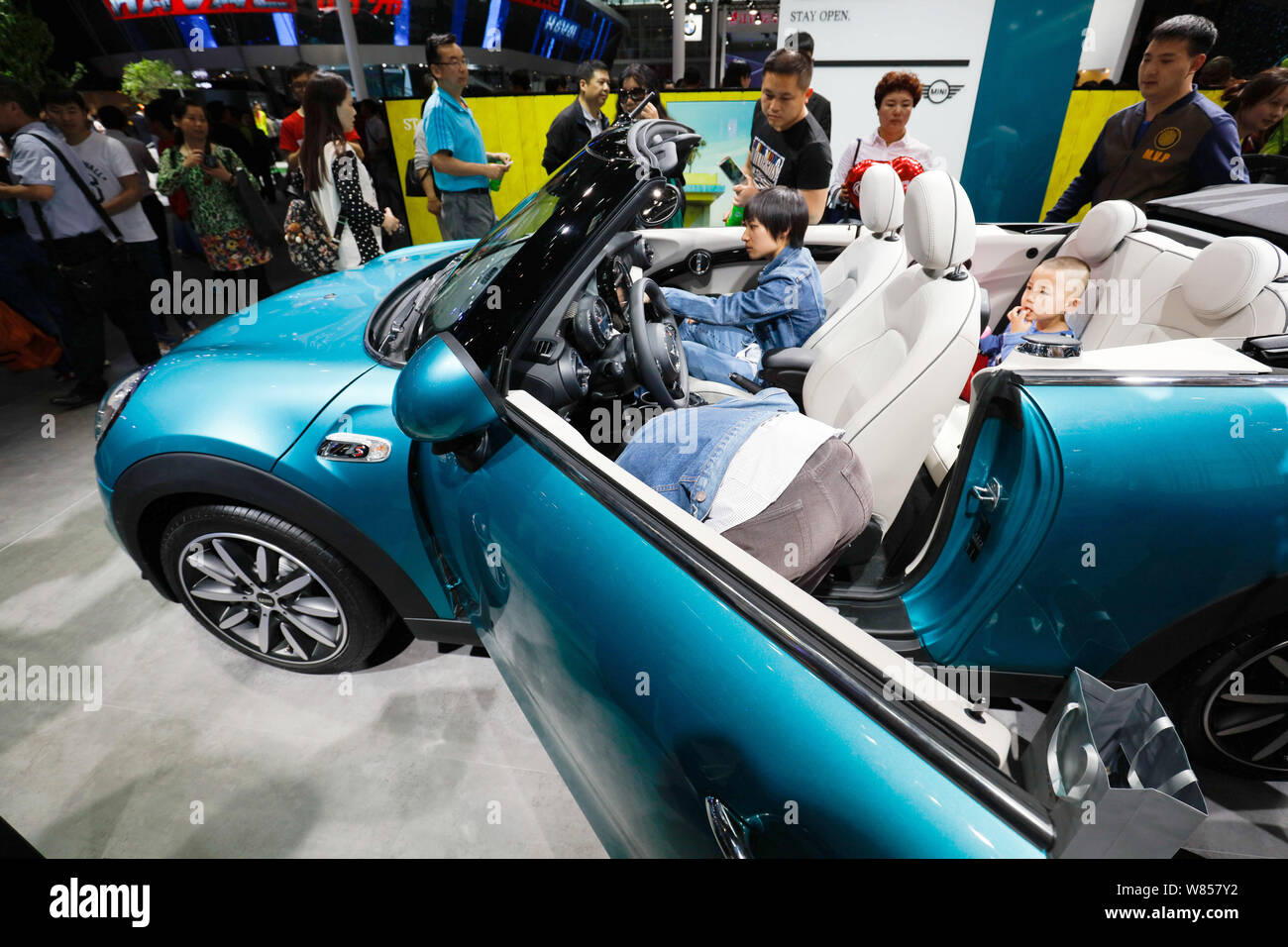 --FILE--Chinese visitors try out or look at a Mini Cooper on display ...
